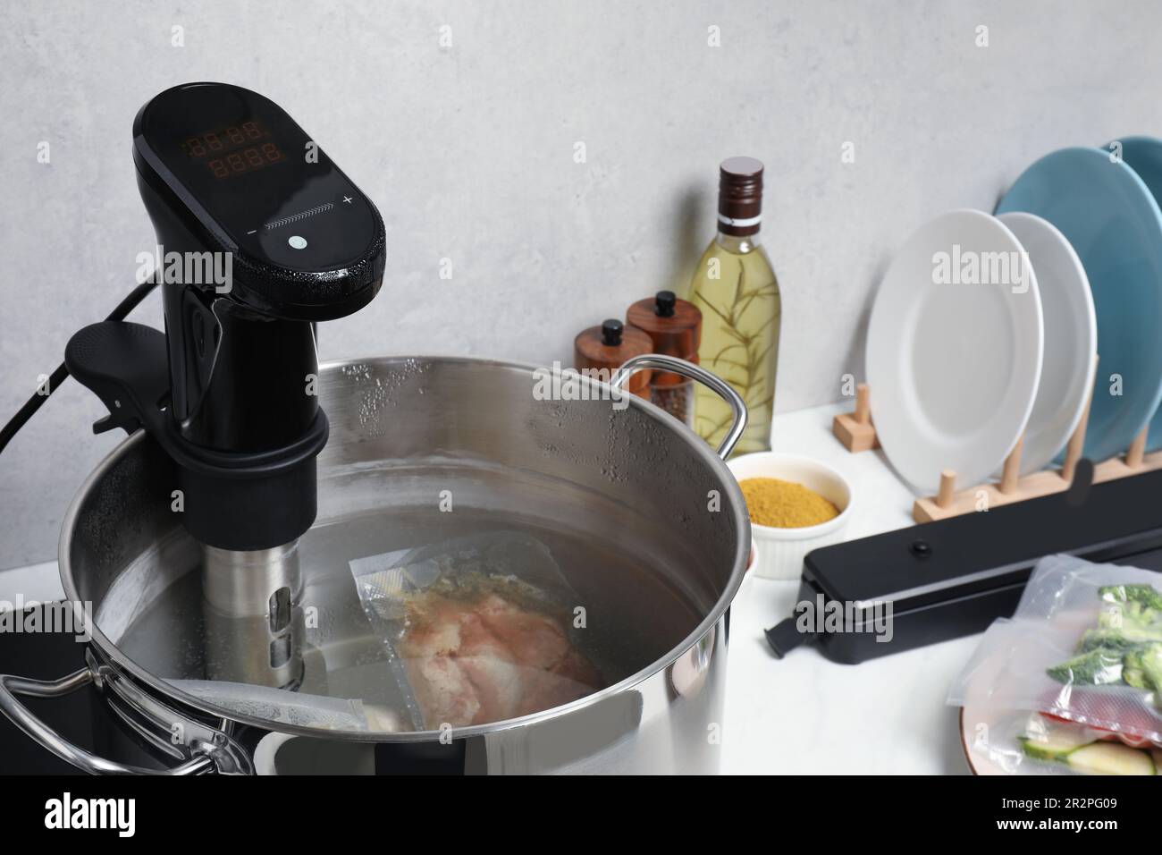 Thermal immersion circulator and vacuum packed meat in pot on table ...