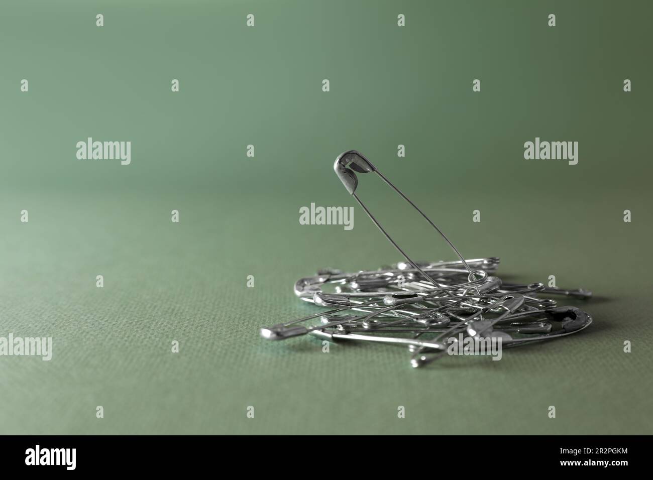 Pile of safety pins on green background, space for text Stock Photo - Alamy