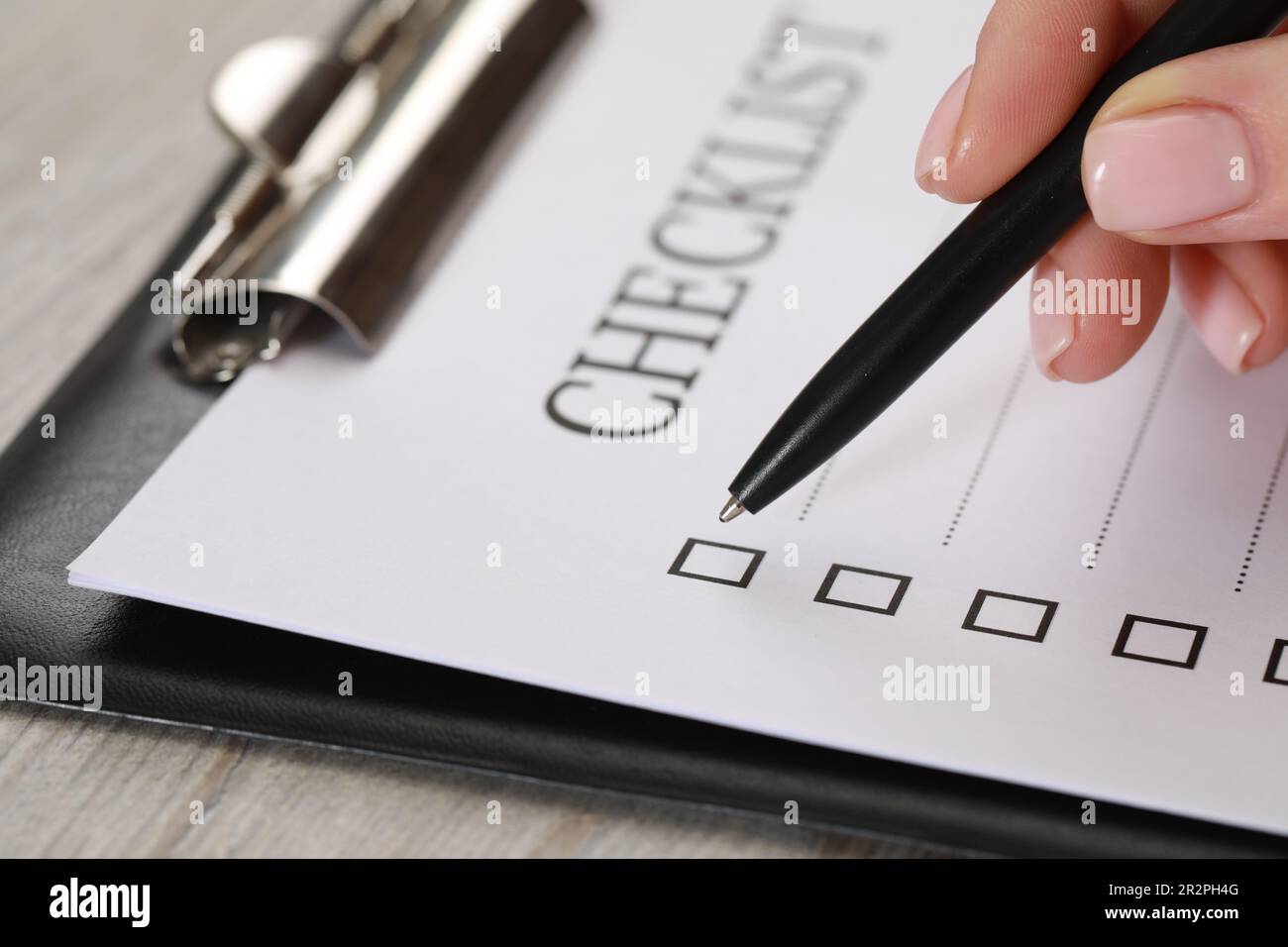 Woman filling Checklist at wooden table, closeup Stock Photo - Alamy