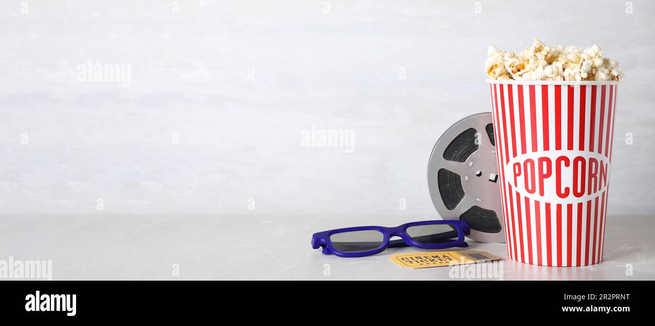 Delicious popcorn, glasses, cinema ticket and tape on light table ...