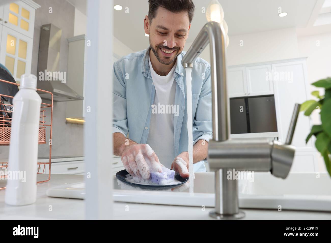 Man washing plate above sink in kitchen, view from outside Stock Photo ...