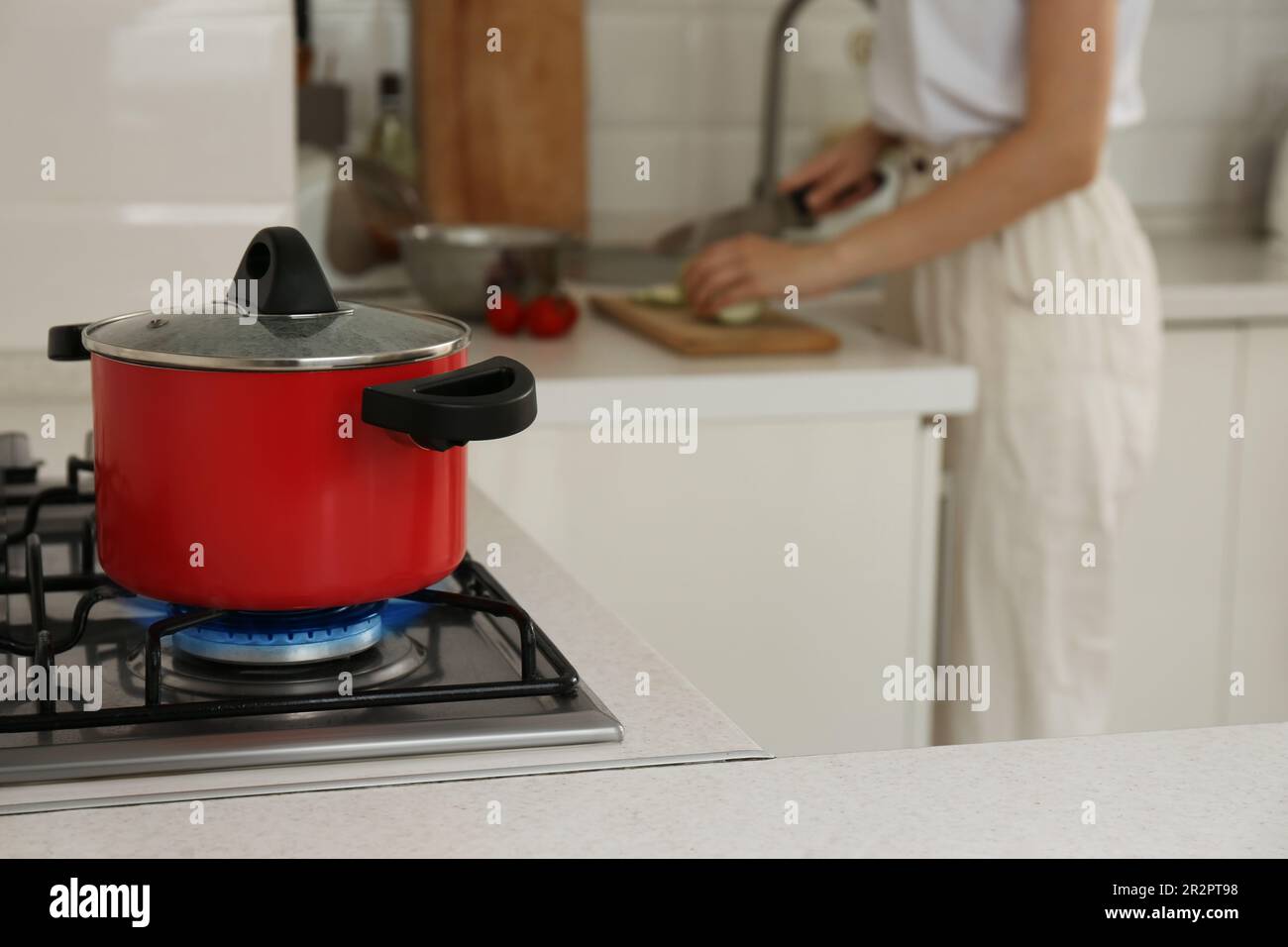 Woman cooking food in kitchen, focus on gas stove with red pot Stock ...