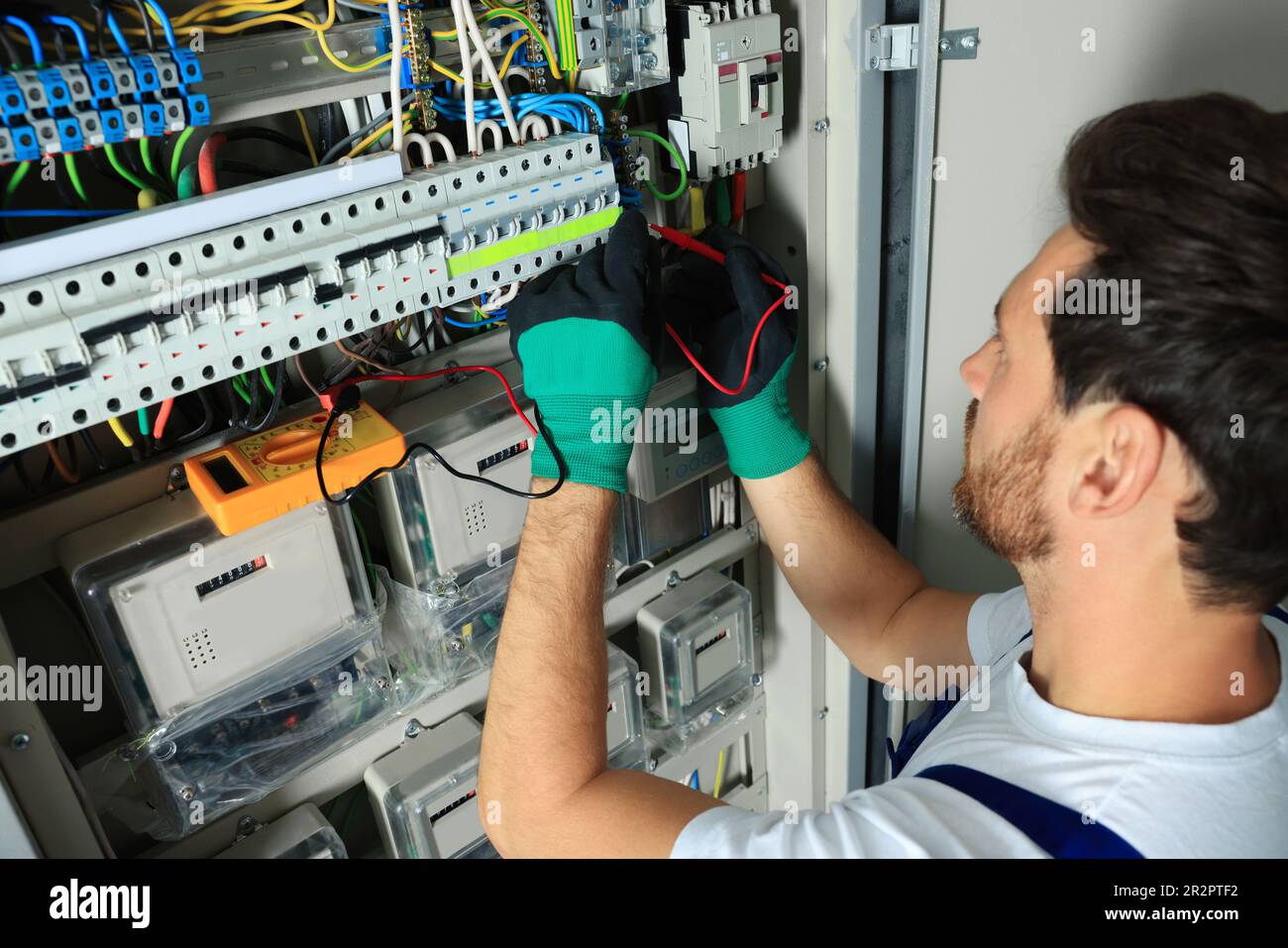 Electrician checking electric current with multimeter indoors, closeup ...