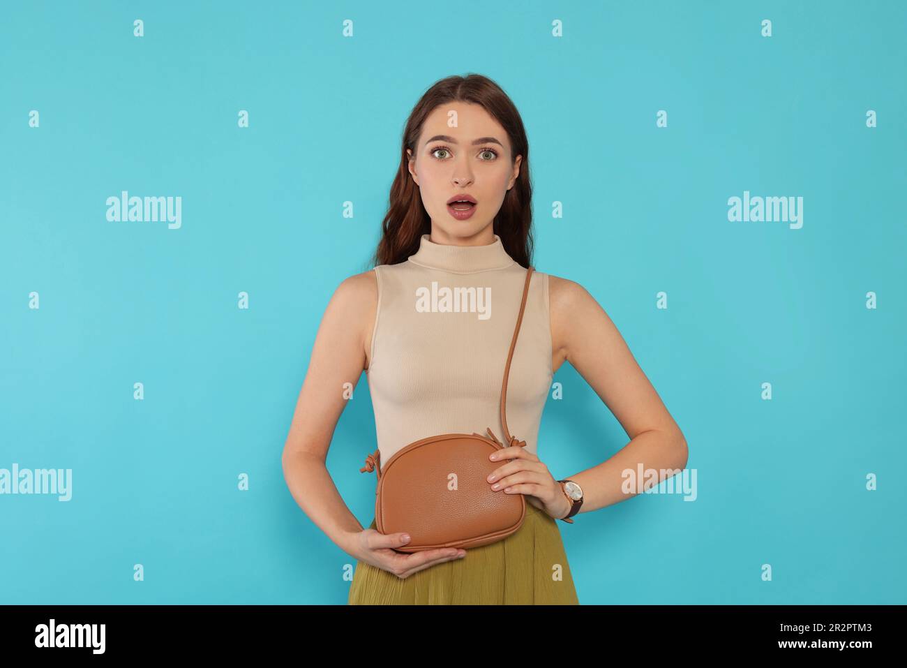 Emotional young woman in fashionable outfit with stylish bag on light ...