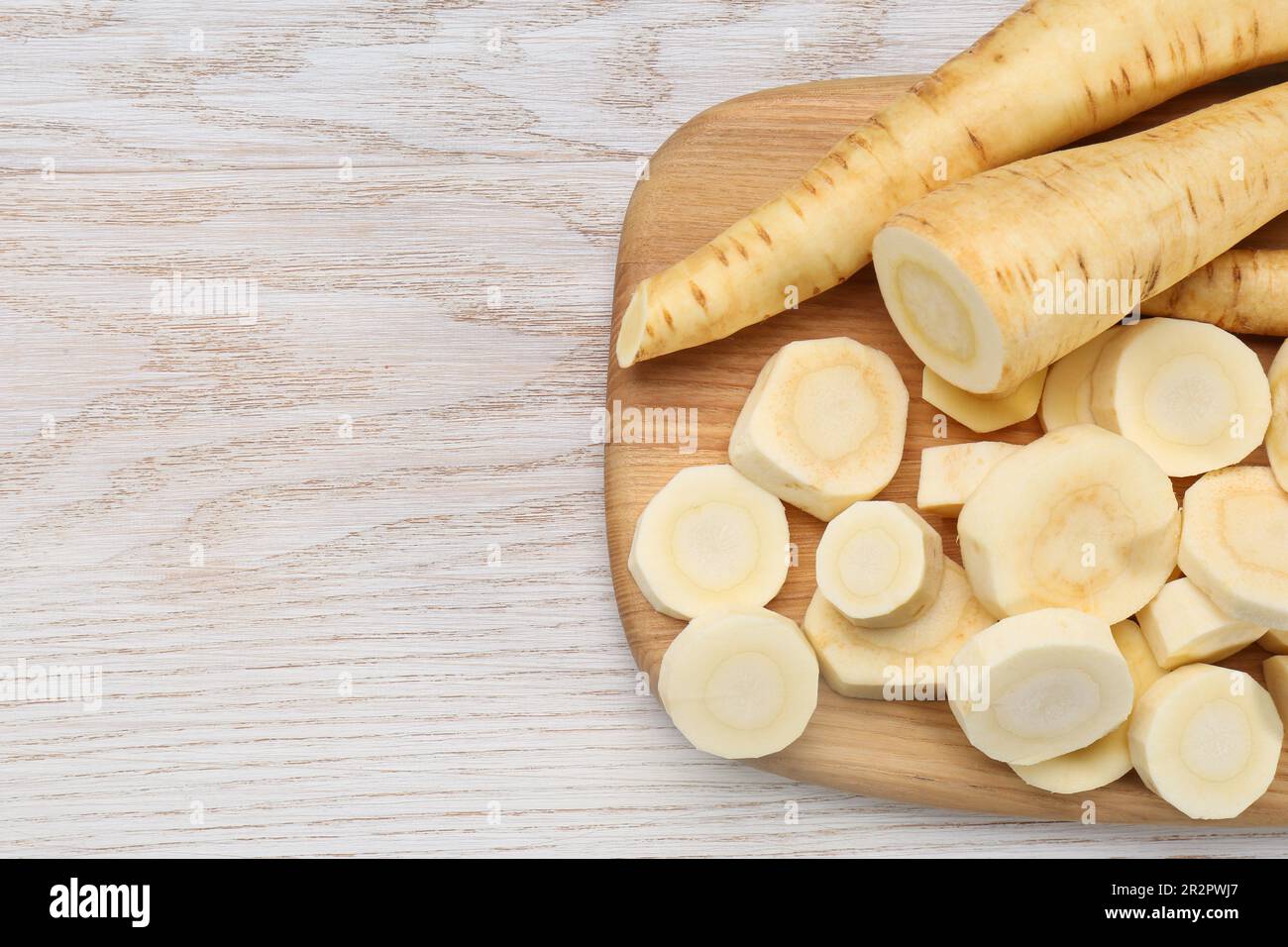 Whole and cut fresh ripe parsnips on white wooden table, top view ...