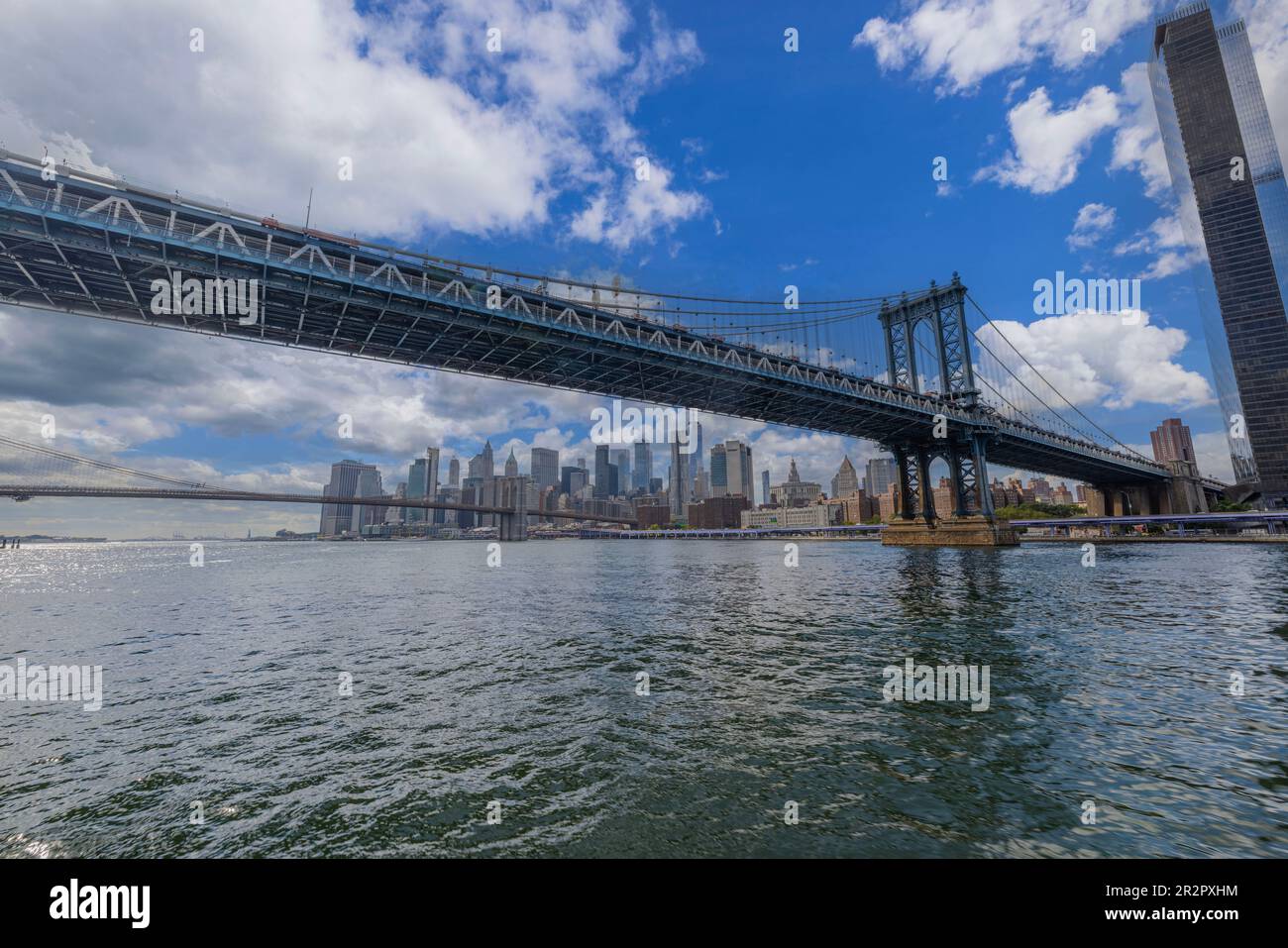 Beautiful view of Brooklyn Bridge over Hudson River and skyscrapers of Manhattan against blue ...