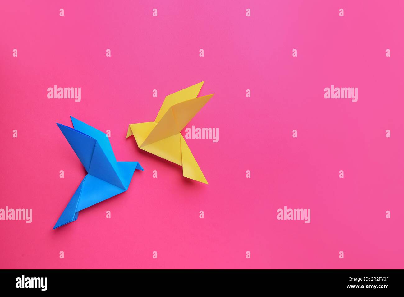 Beautiful colorful origami birds on pink background, flat lay. Space ...