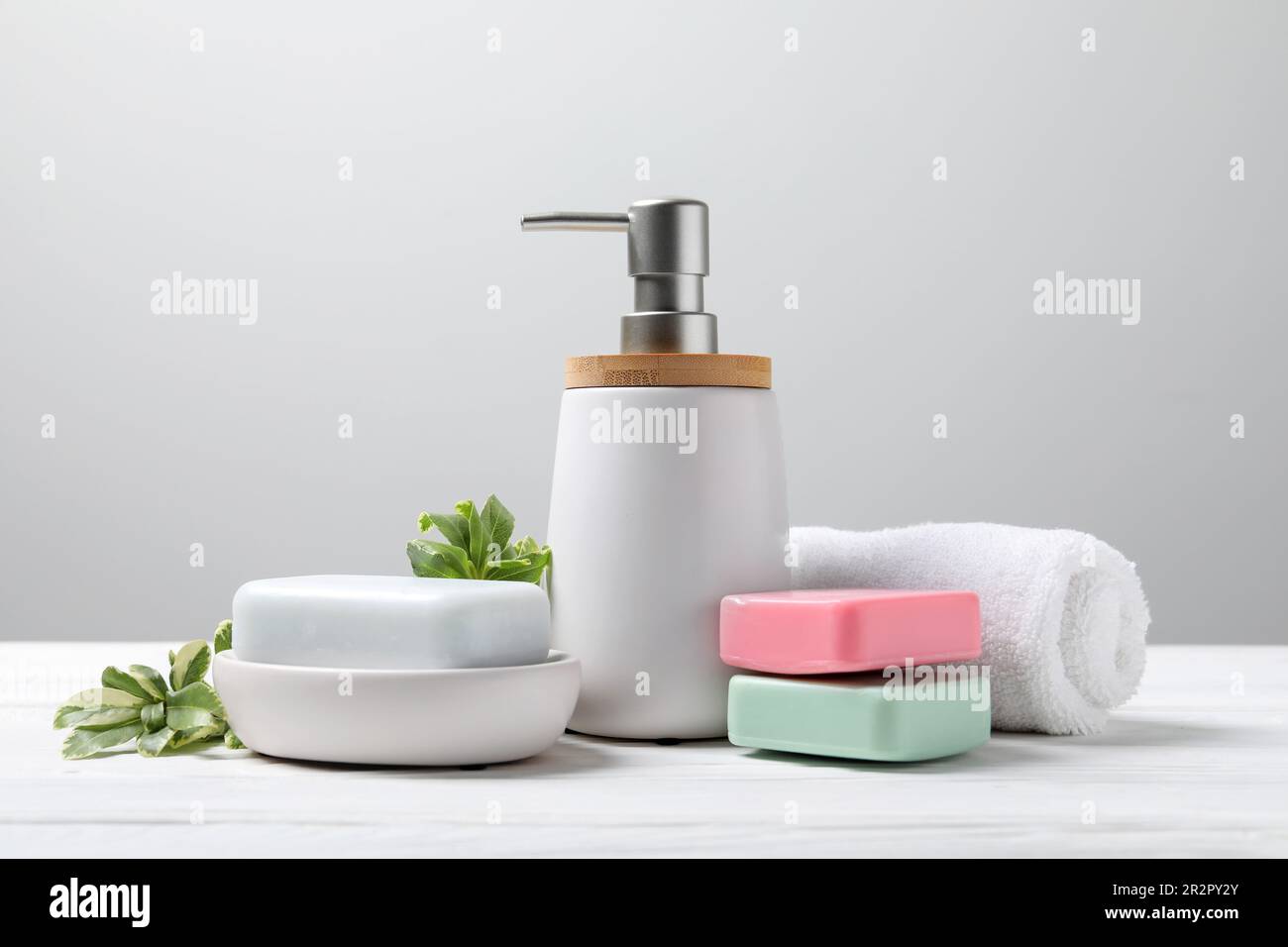 Soap bars, bottle dispenser and towel on table against white background ...