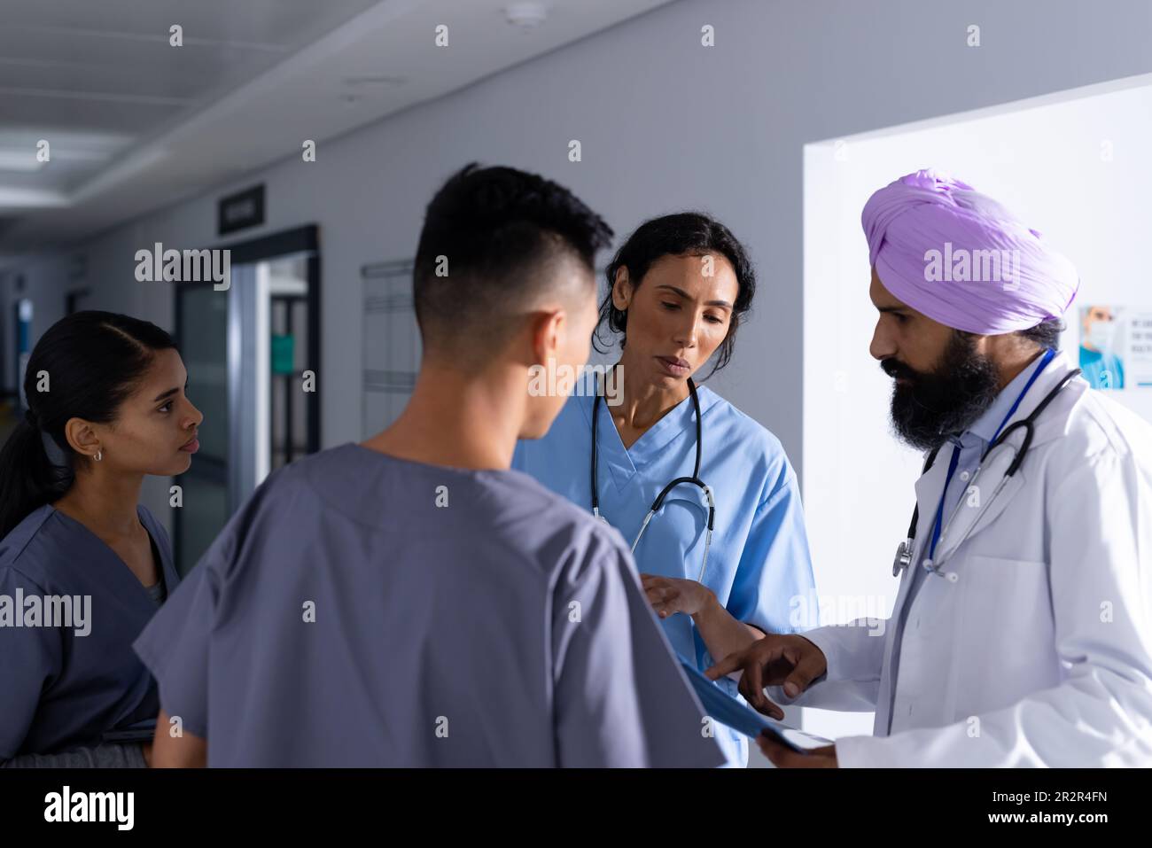 Diverse male and female doctors discussing x ray in corridor at ...