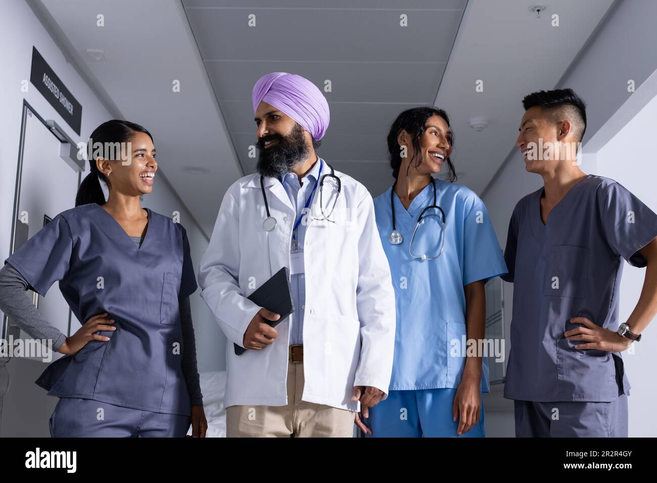 Happy diverse male and female doctors smiling at each other in corridor ...