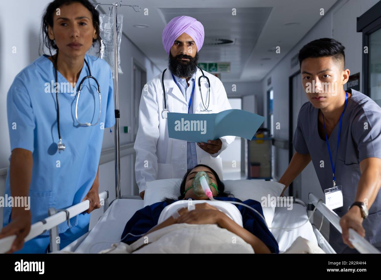 Diverse male and female doctors pushing female patient lying in bed in ...