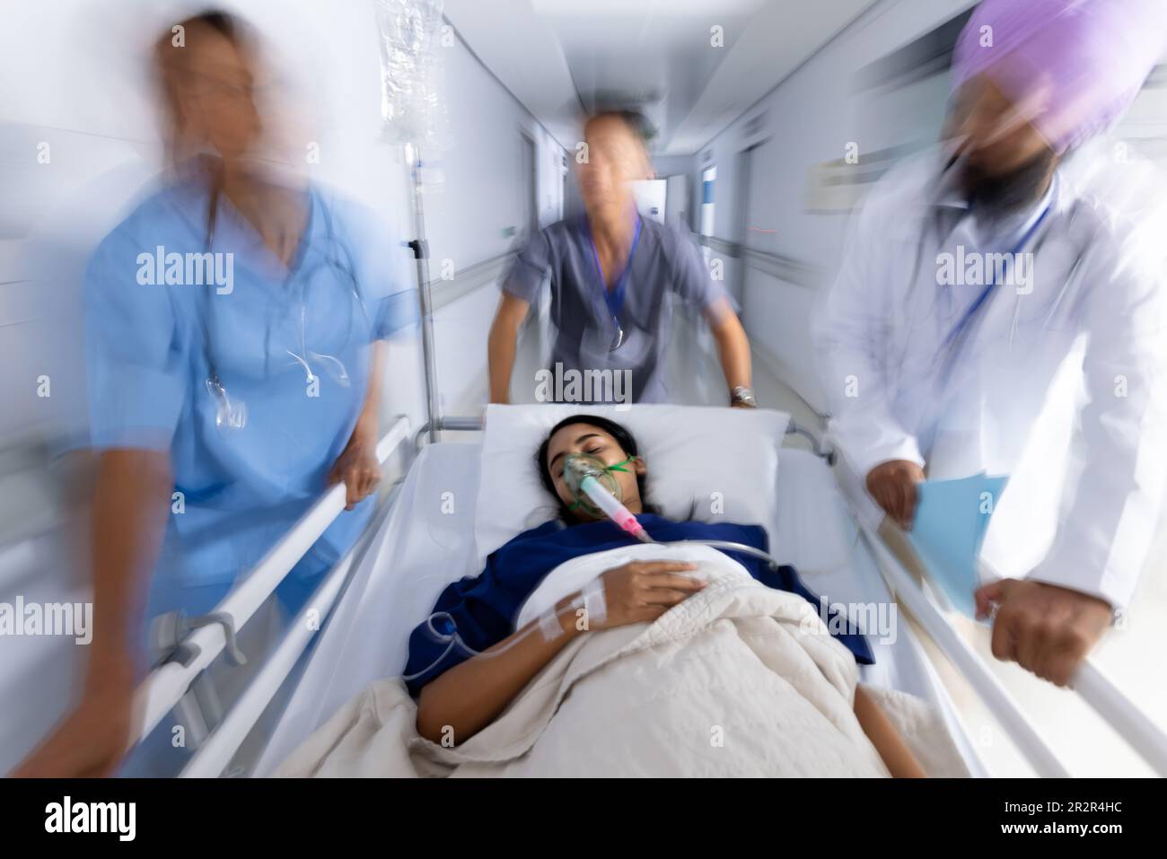 Diverse male and female doctors pushing female patient in bed in ...