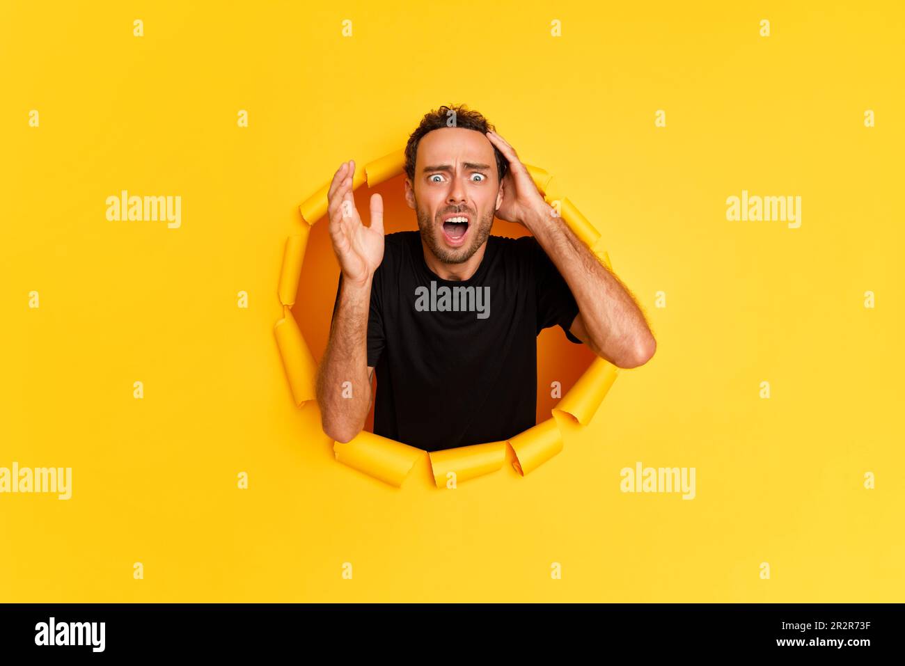 Frightened guy in black T-shirt posing inside in middle of yellow ...