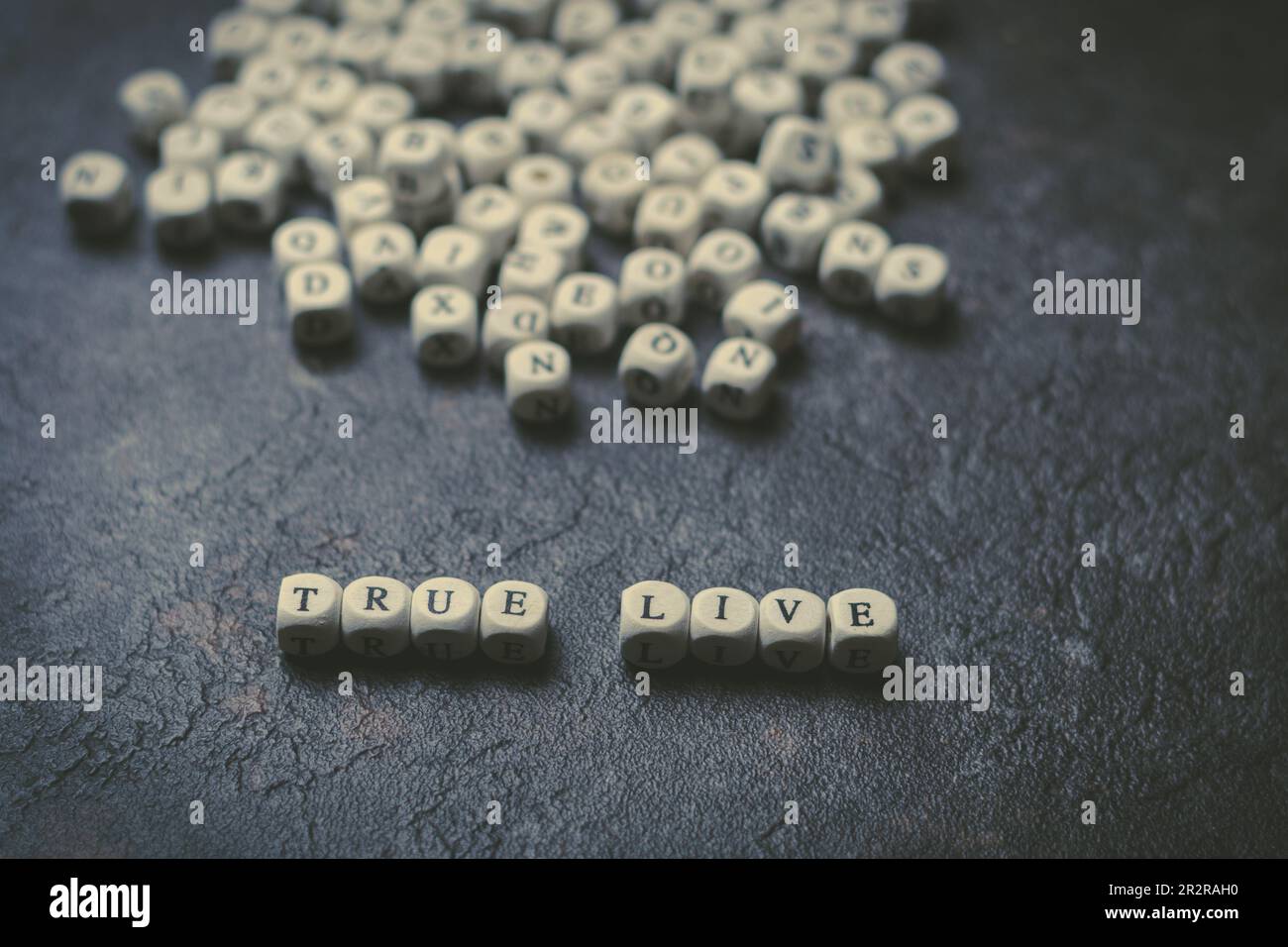 Letras en cubos de madera formando la frase true live en fondo negro ...