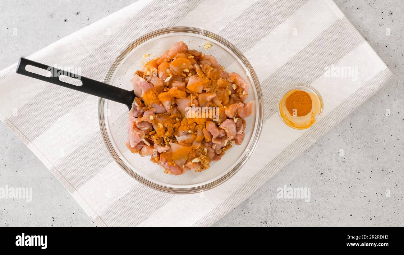 Adding turmeric to chopped chicken . Glass bowl with the chopped ...