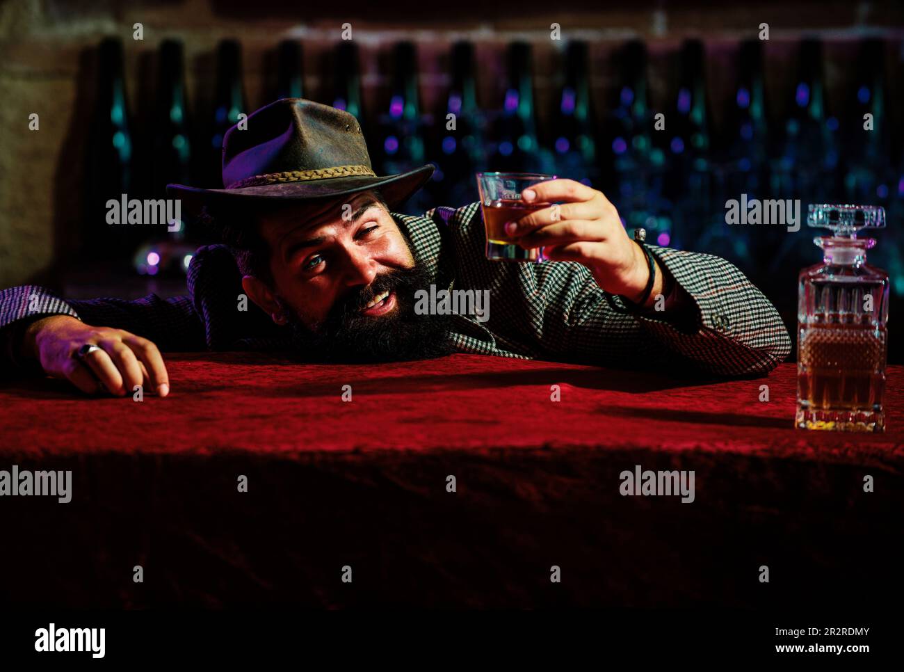 After drinking in pub or bar. Sleepy drunk young man lying on table and sleeping with empty ...