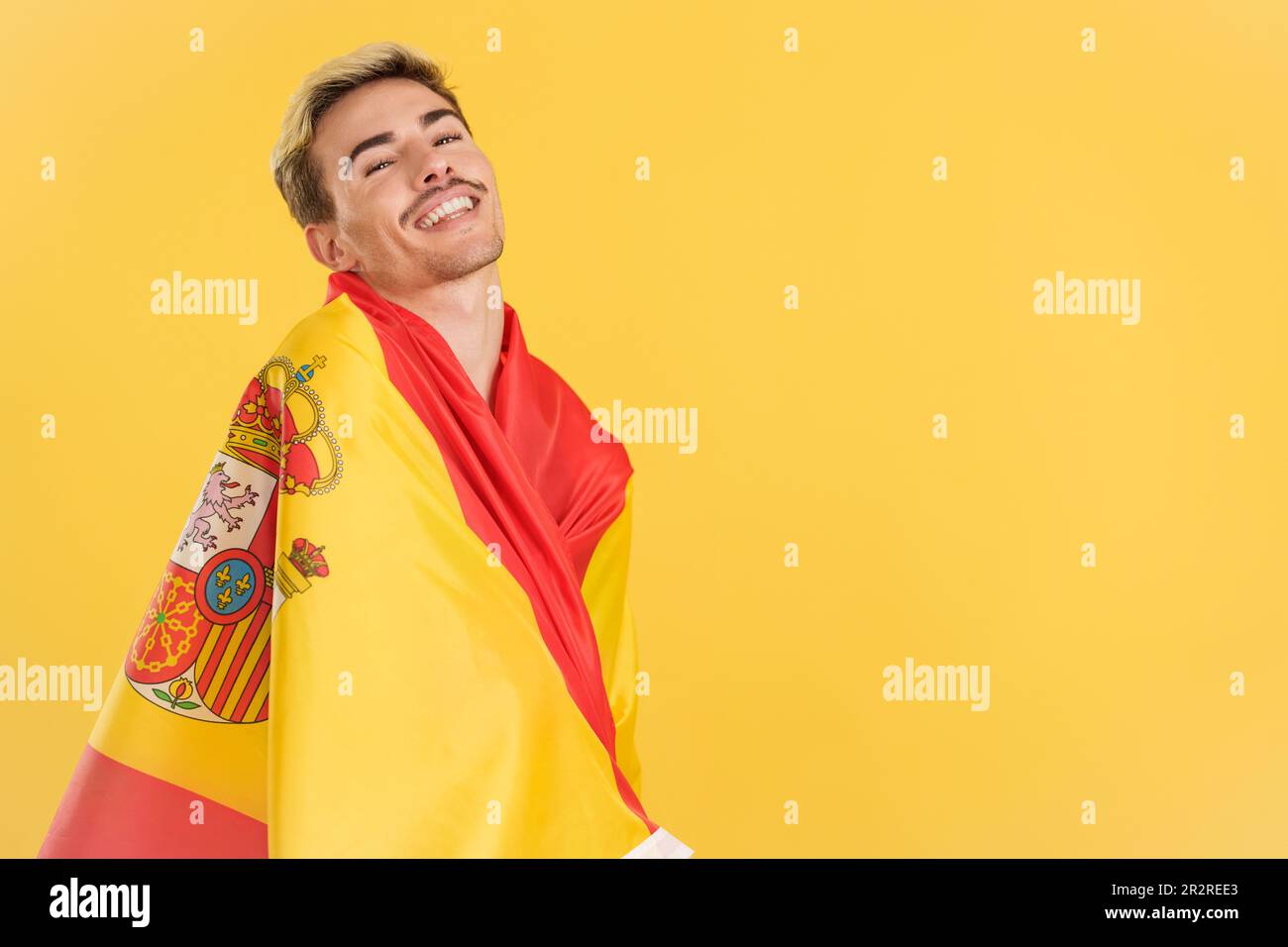 Happy gay man wrapping with a spanish national flag Stock Photo - Alamy