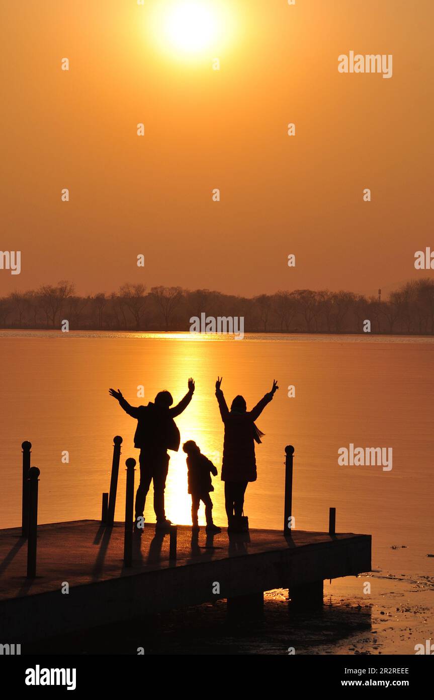 Silhouettes of Happy family on backdrop of sea, sun, clouds Background ...