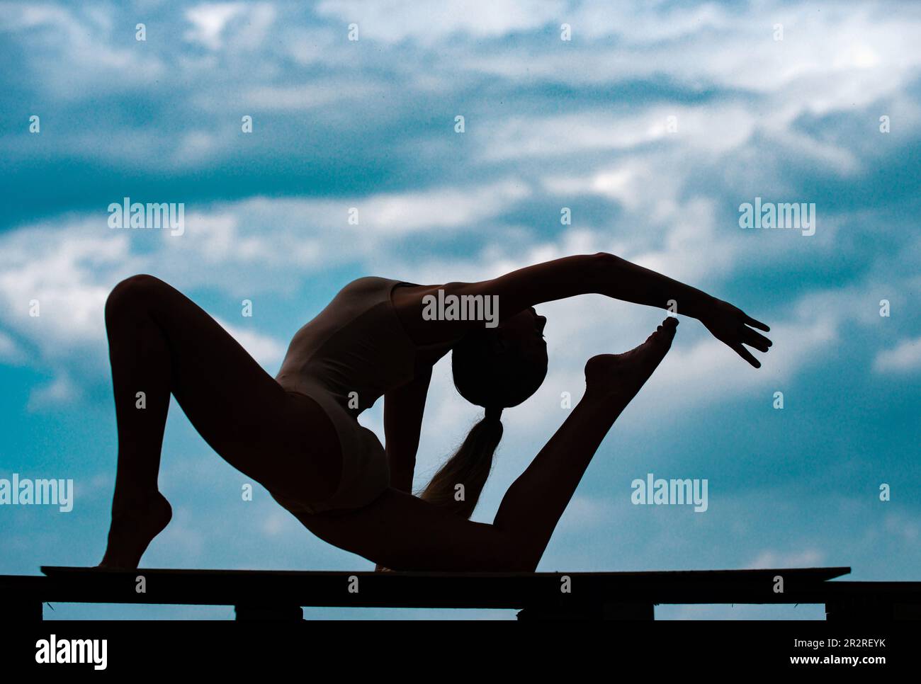 Silhouette of female fit model on loudy sky background. Stretching and ...