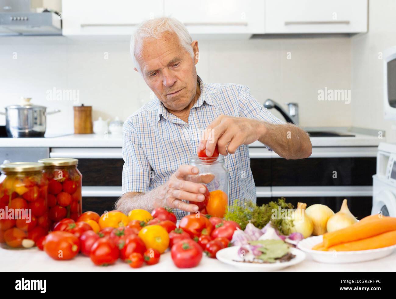old gray haired man makes harvests for the winter pickles tomatoes ...