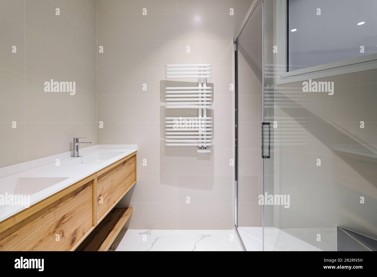 Modern bathroom with wooden base for white sinks. Radiator for warm ...