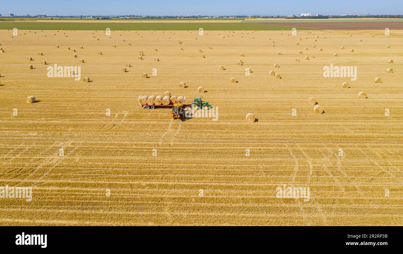 Above view on excavator as loading straw bales on trailer, tow by ...