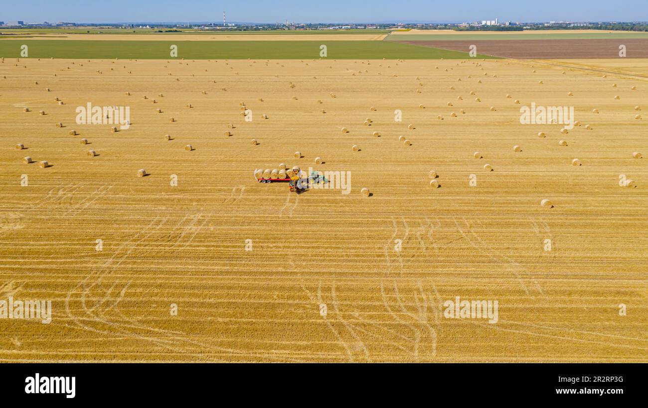 Above view on excavator as loading straw bales on trailer, tow by ...