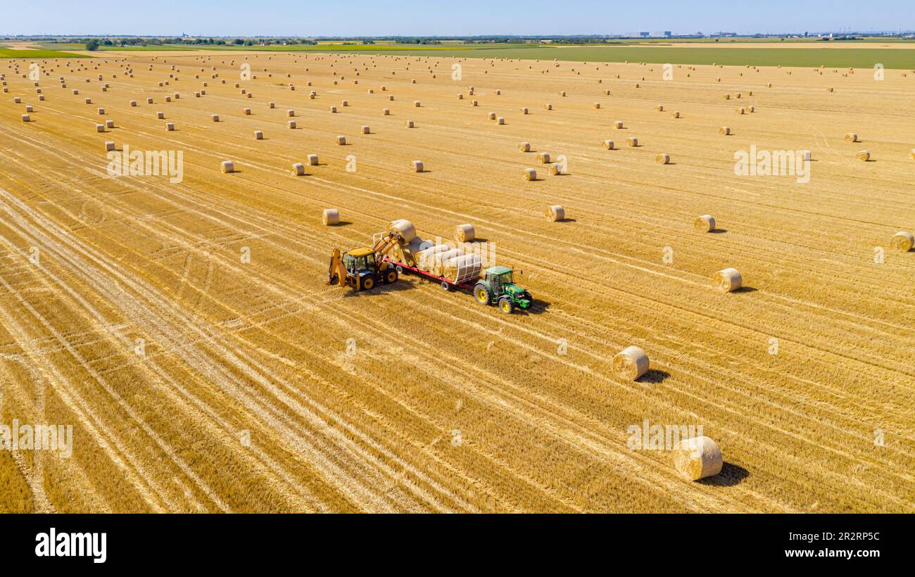 Above view on excavator as loading straw bales on trailer, tow by ...