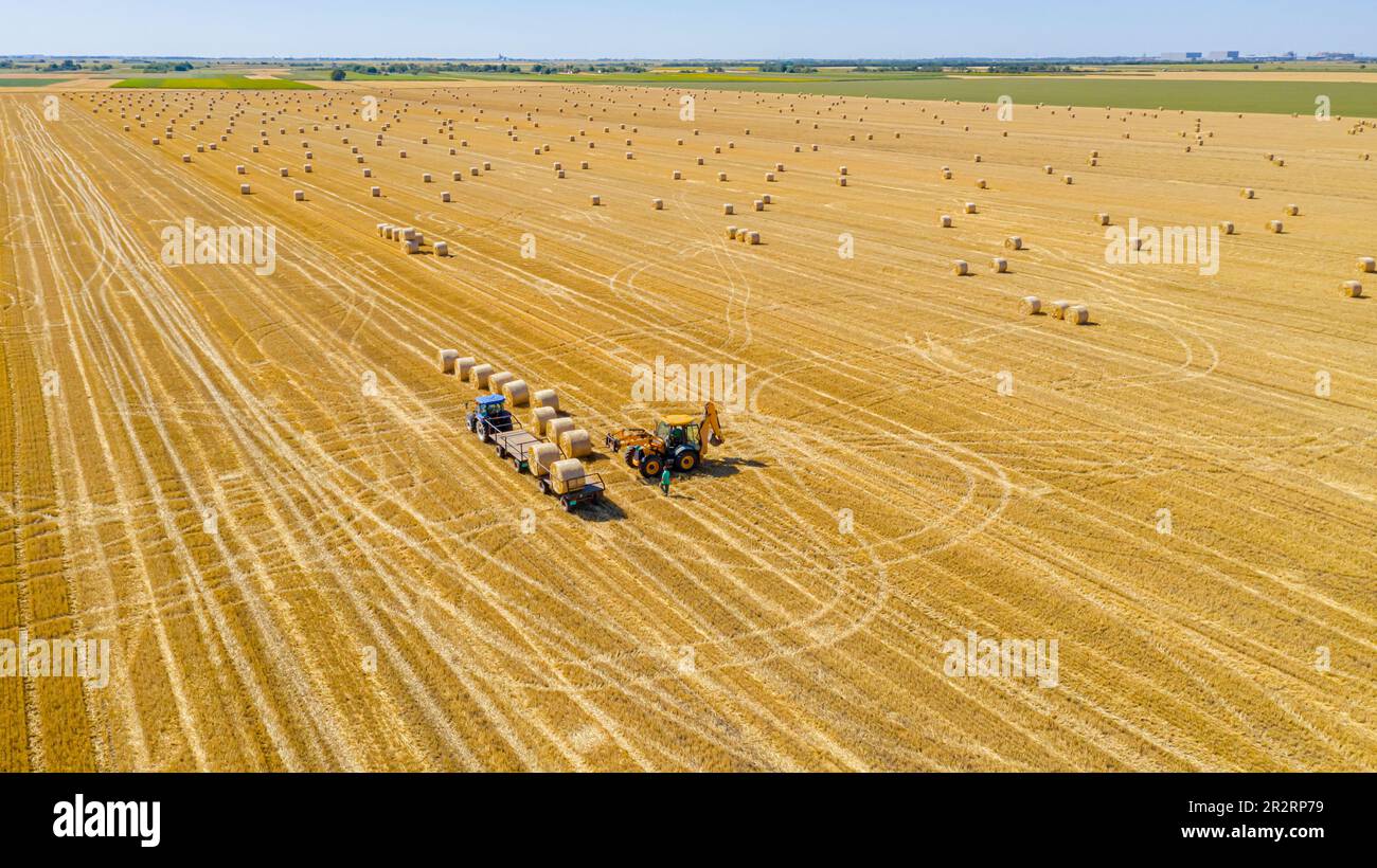 Above view on excavator as loading straw bales on trailer, tow by ...