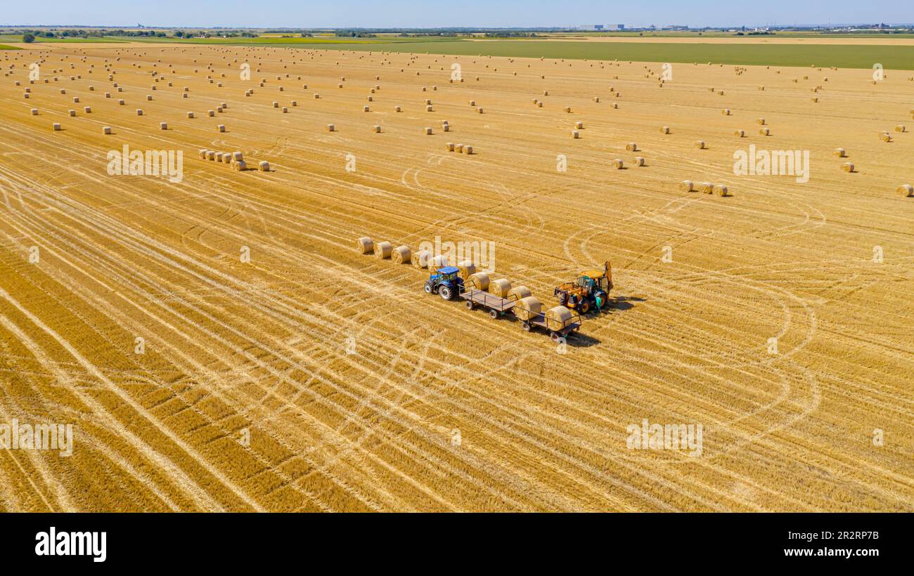 Above view on excavator as loading straw bales on trailer, tow by ...