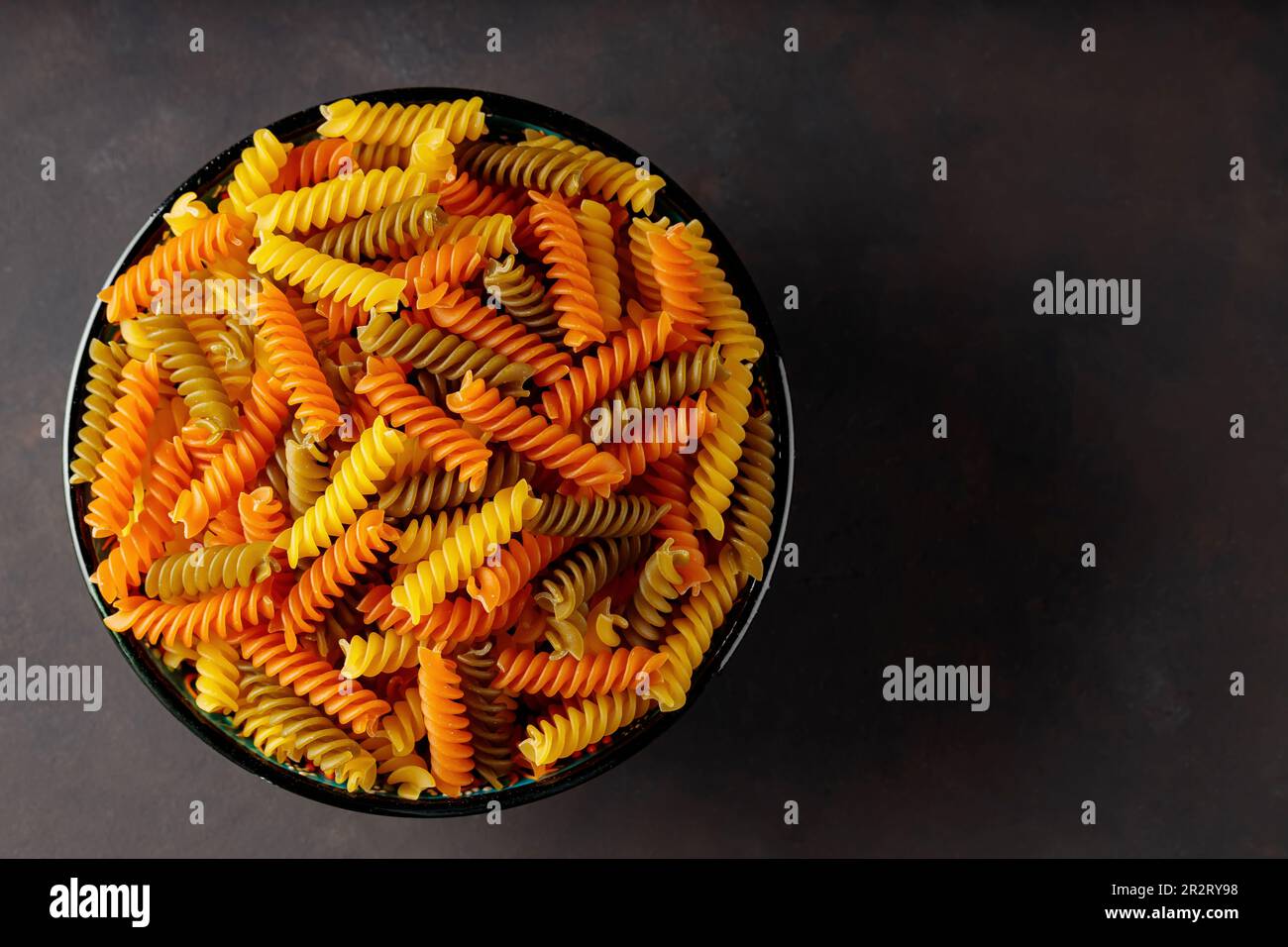 Fusilli dry pasta on a dark background. Tricolor fusilli pasta in a ...
