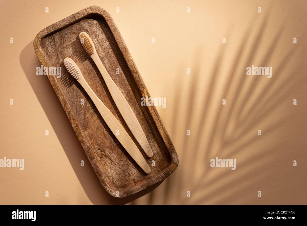 Eco-friendly bamboo toothbrushes with shadow of palm leaf on yellow ...