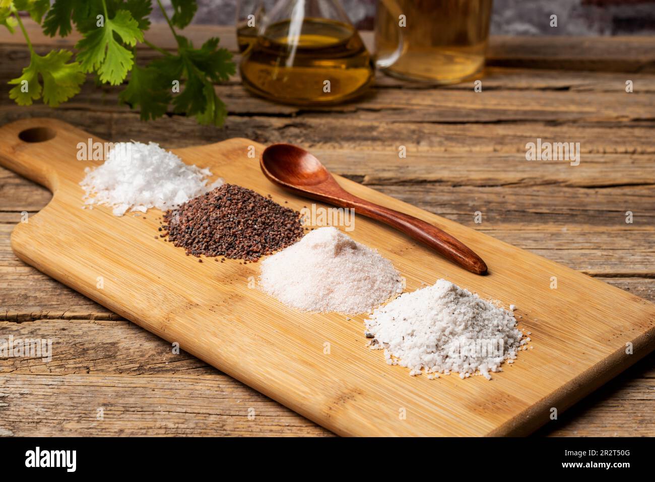 Wooden board with piles of different types of salt, black, pink, flake ...