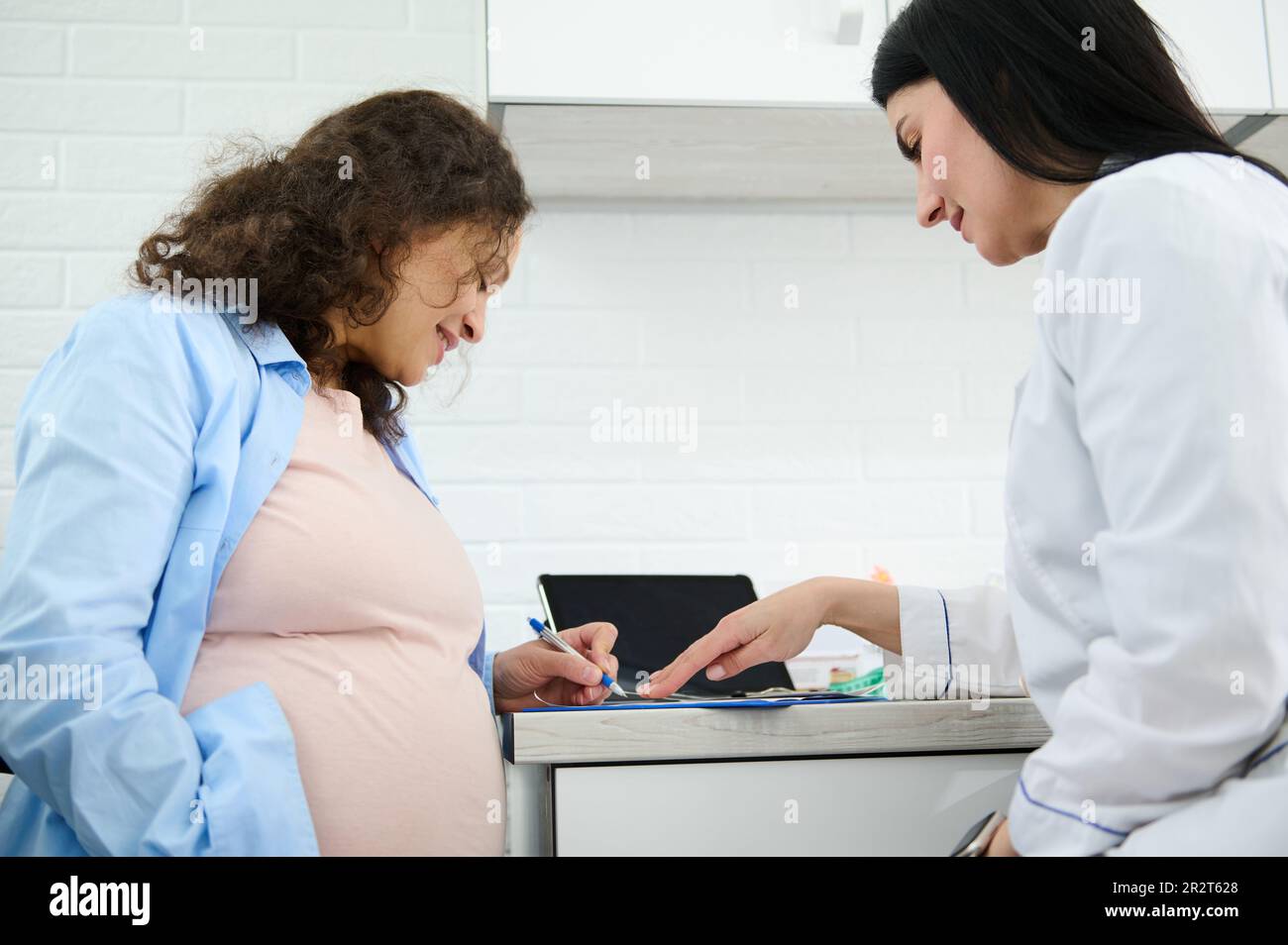 Pregnant woman signing declaration with doctor, concluding agreement on ...