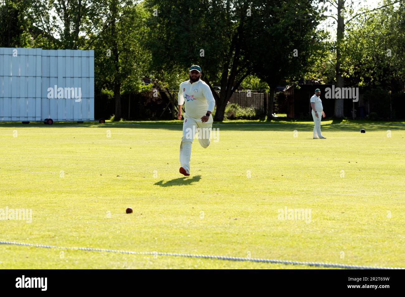 Club cricket, Warwick, England, UK. A fielder chasing the ball to the ...
