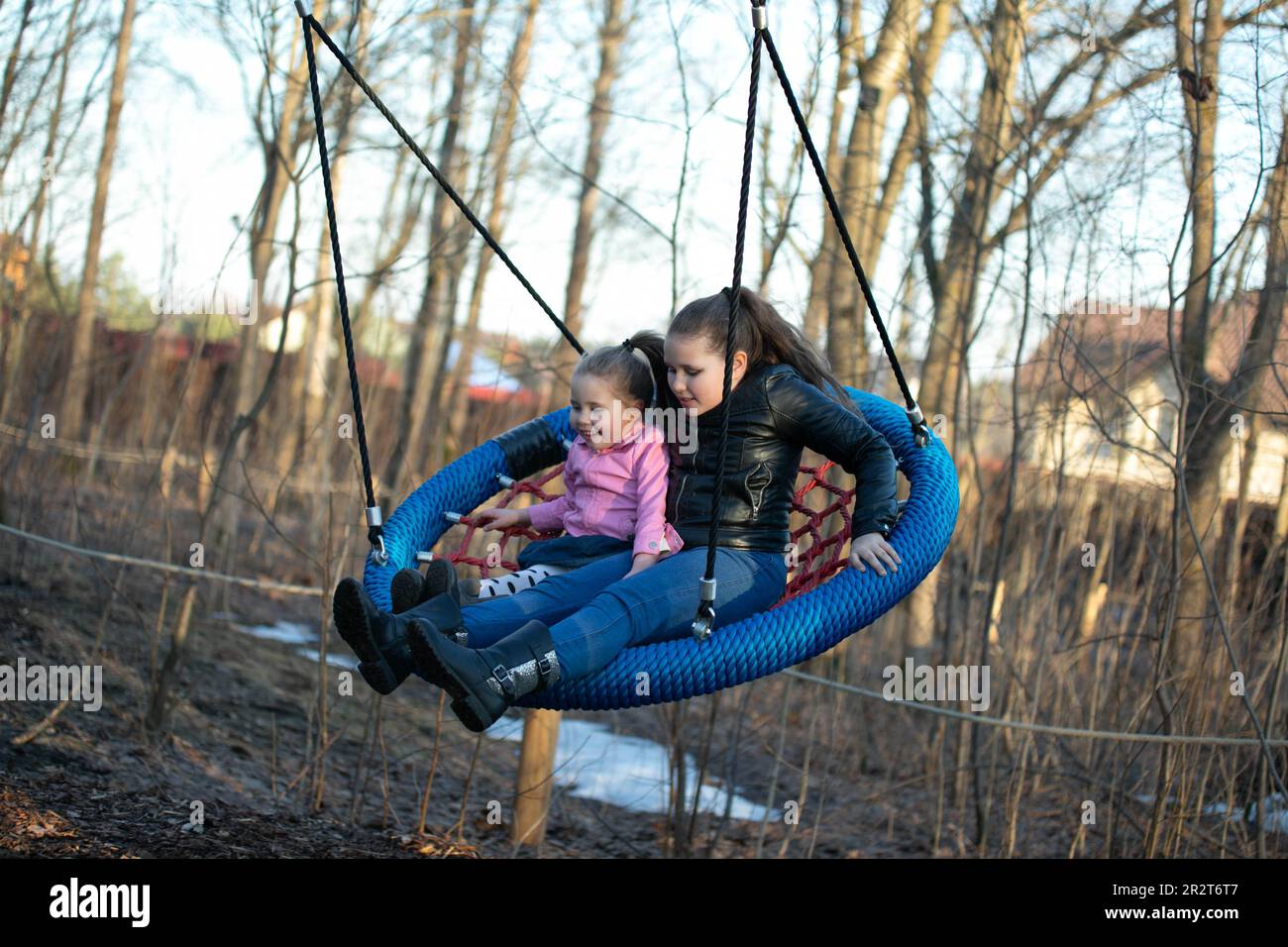 2 girls swinging on a swing Stock Photo - Alamy