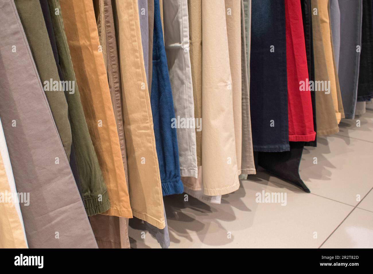 line up pants of different colors in the market. hanging on a rack. a ...