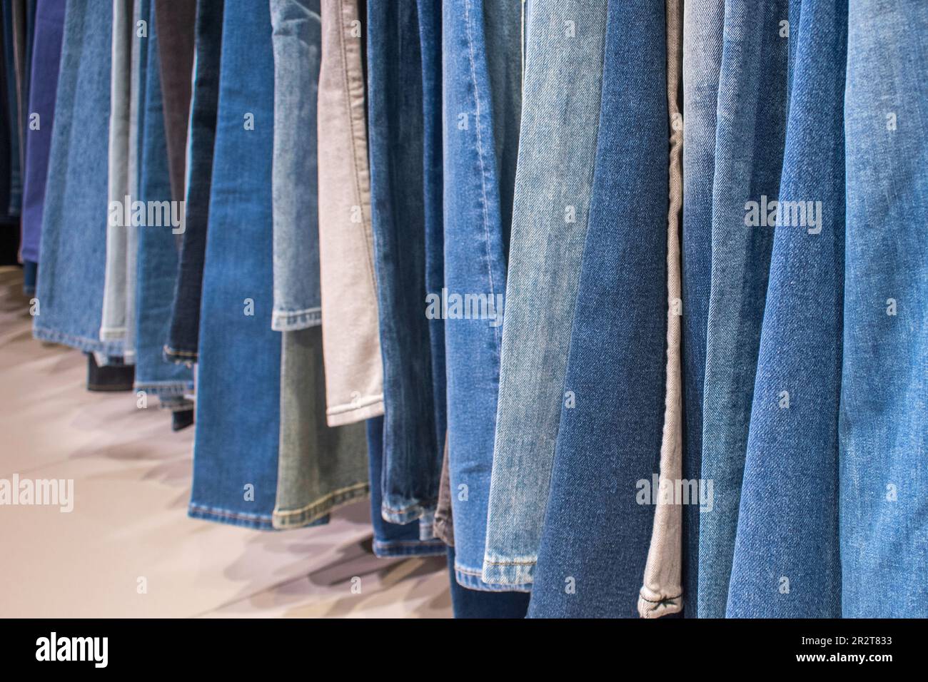line up pants of different colors in the market. hanging on a rack. a ...