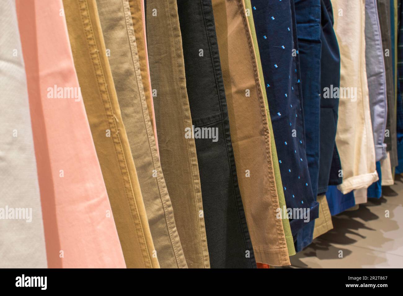 line up pants of different colors in the market. hanging on a rack. a ...