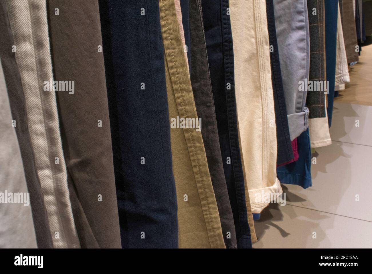 line up pants of different colors in the market. hanging on a rack. a ...
