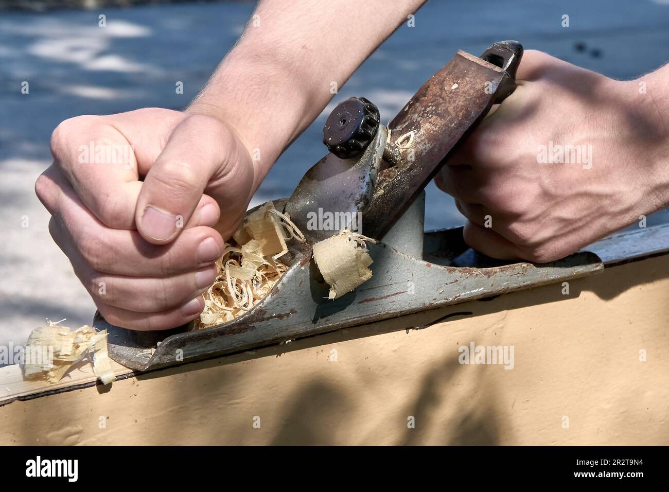 A carpenter processes a wooden billet with a hand planer Stock Photo ...