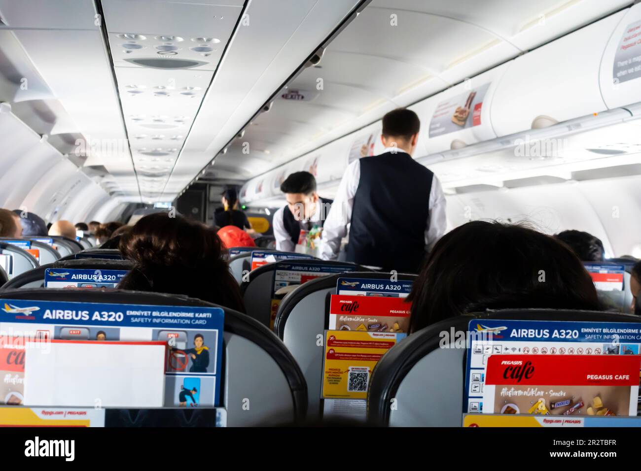 Male flight attendants serving meal and drinks to passengers in an ...