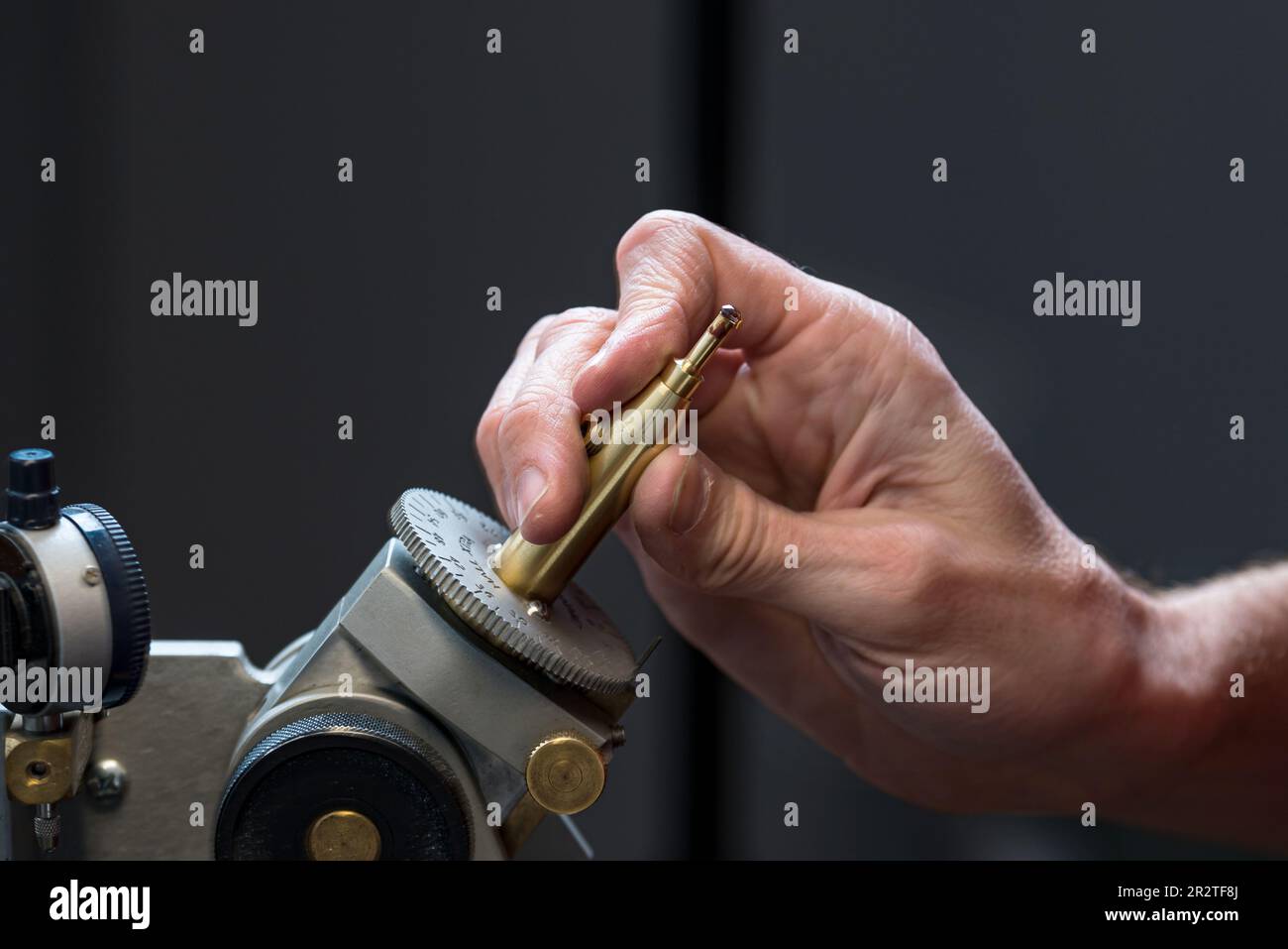 Craftsman's hand holding a metal dop stick with a small round stone ...