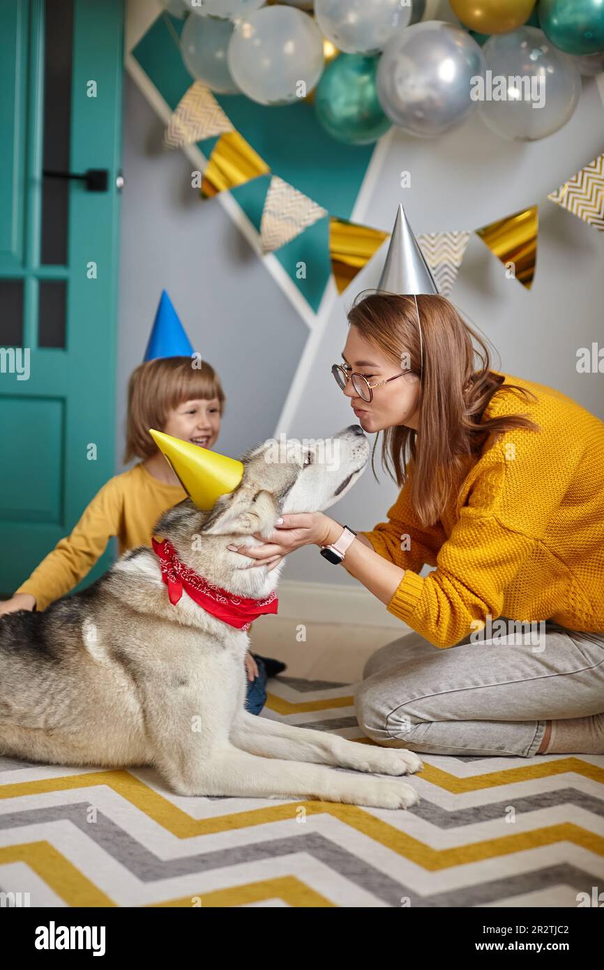 Dog pet birthday, family mother and child hug and kiss their dog ...