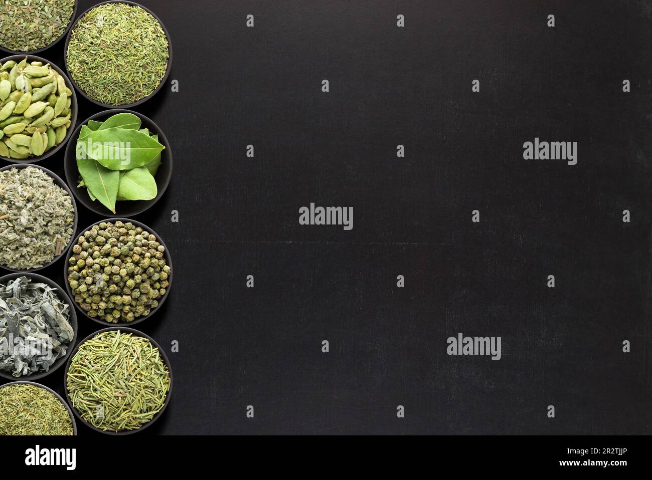 Green spices and herbs on black table with space for recipe. Colorful ...