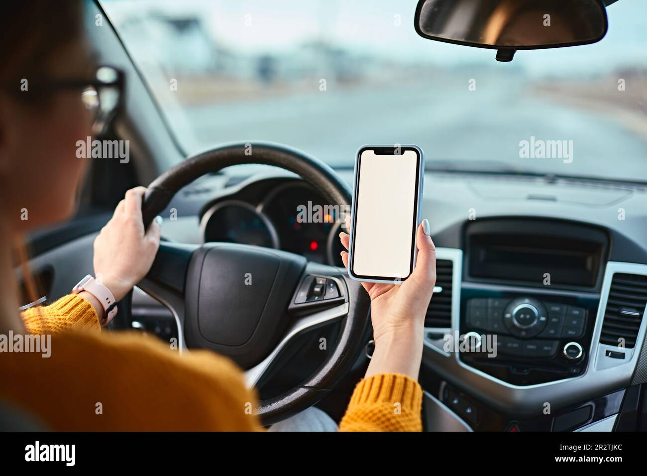 Woman driver using mobile phone screen blank mockup while driving ...