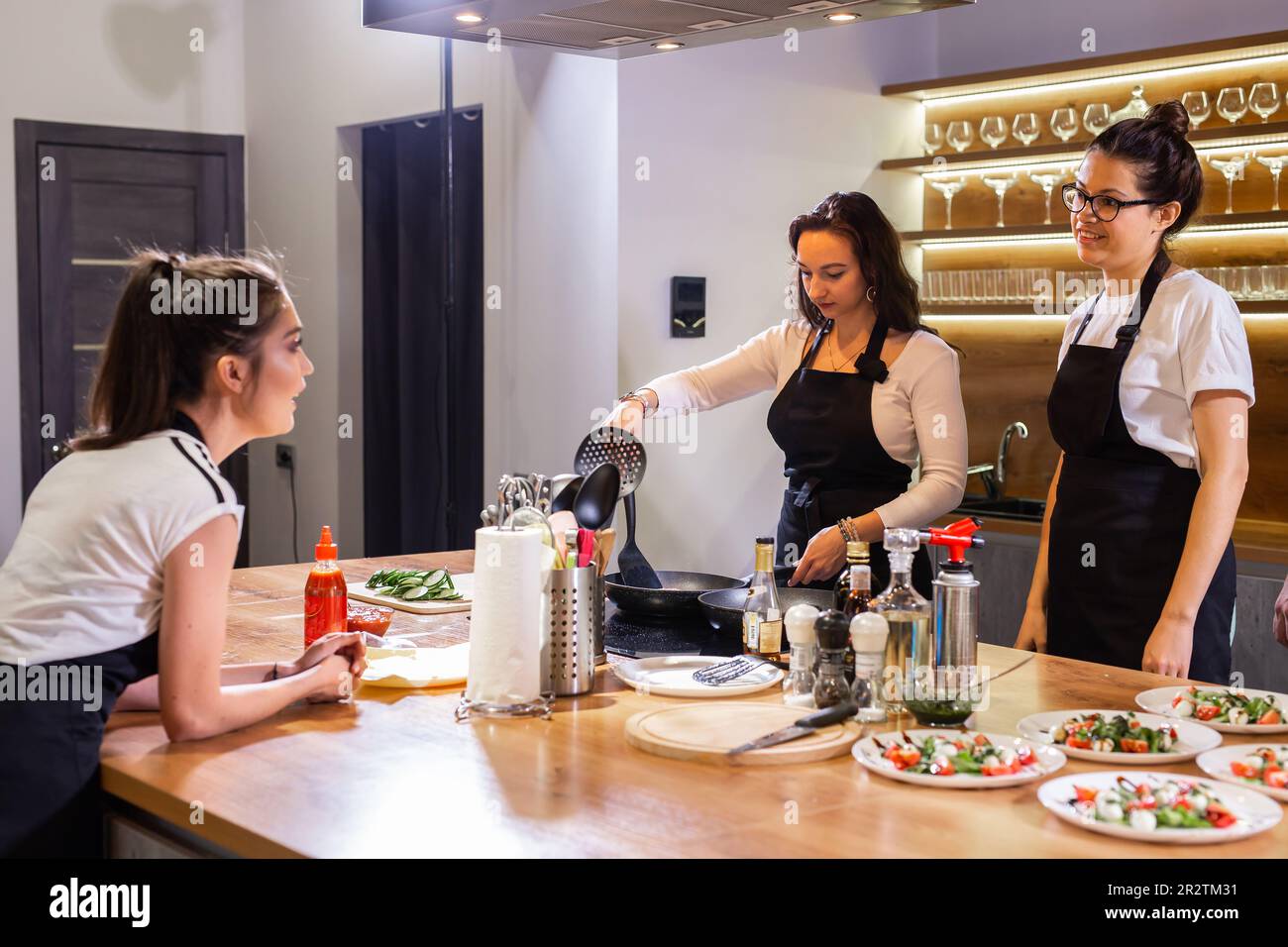 Three funny professional female chefs cooking food in large kitchen and ...