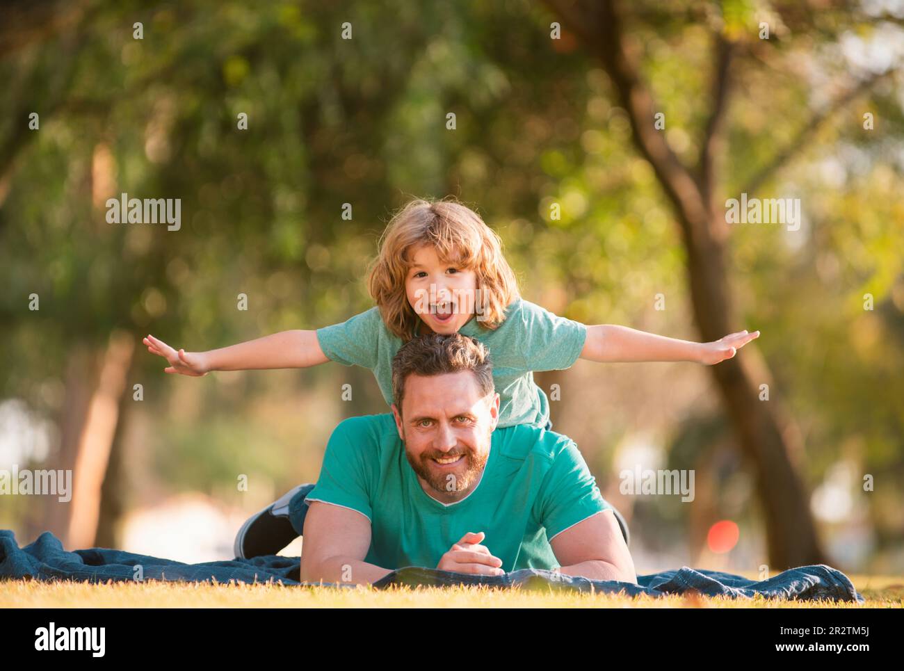Concept of friendly family. Father and son laying on grass in summer ...