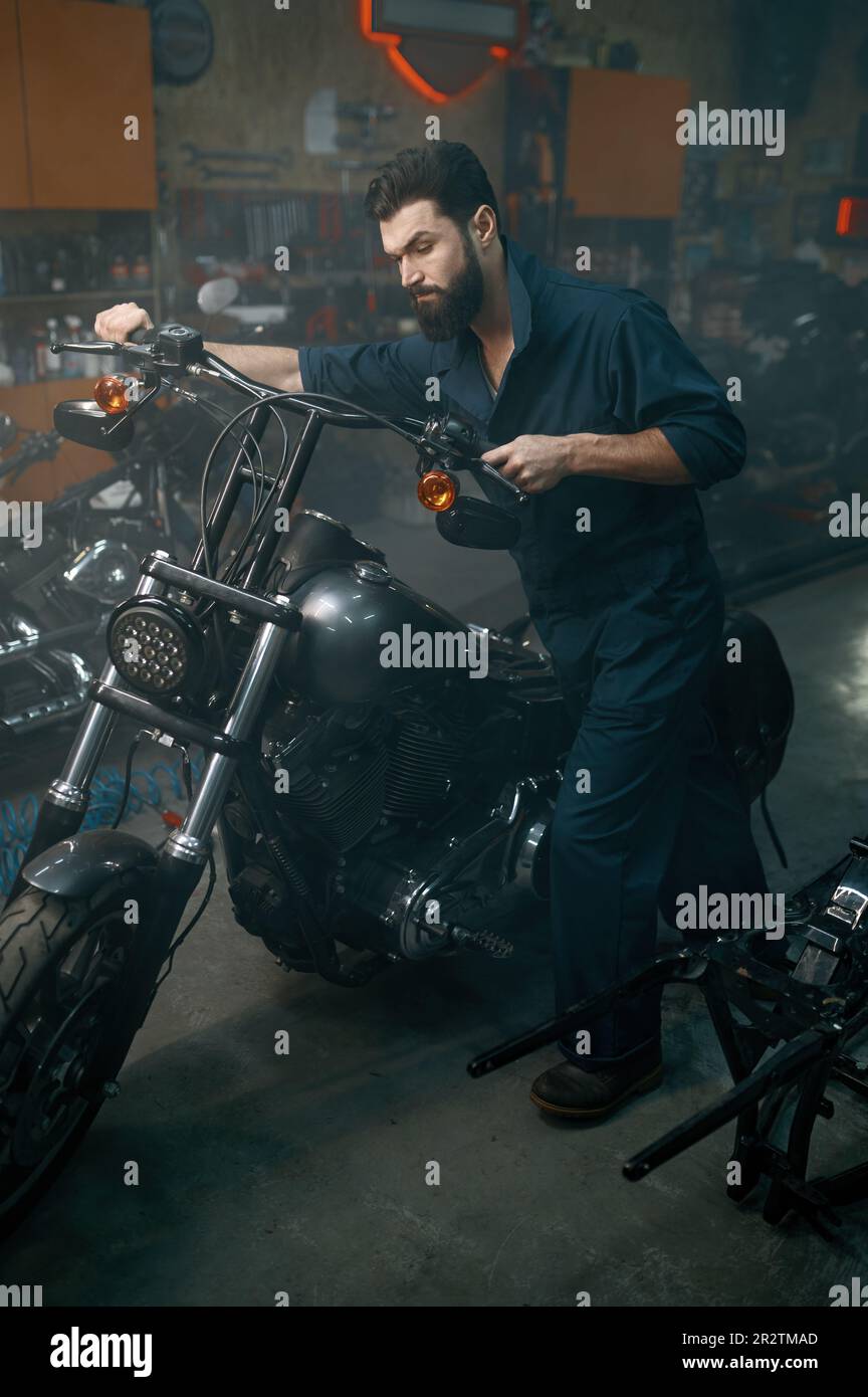 Auto mechanic pushing motorcycle on repair stand in workshop garage ...