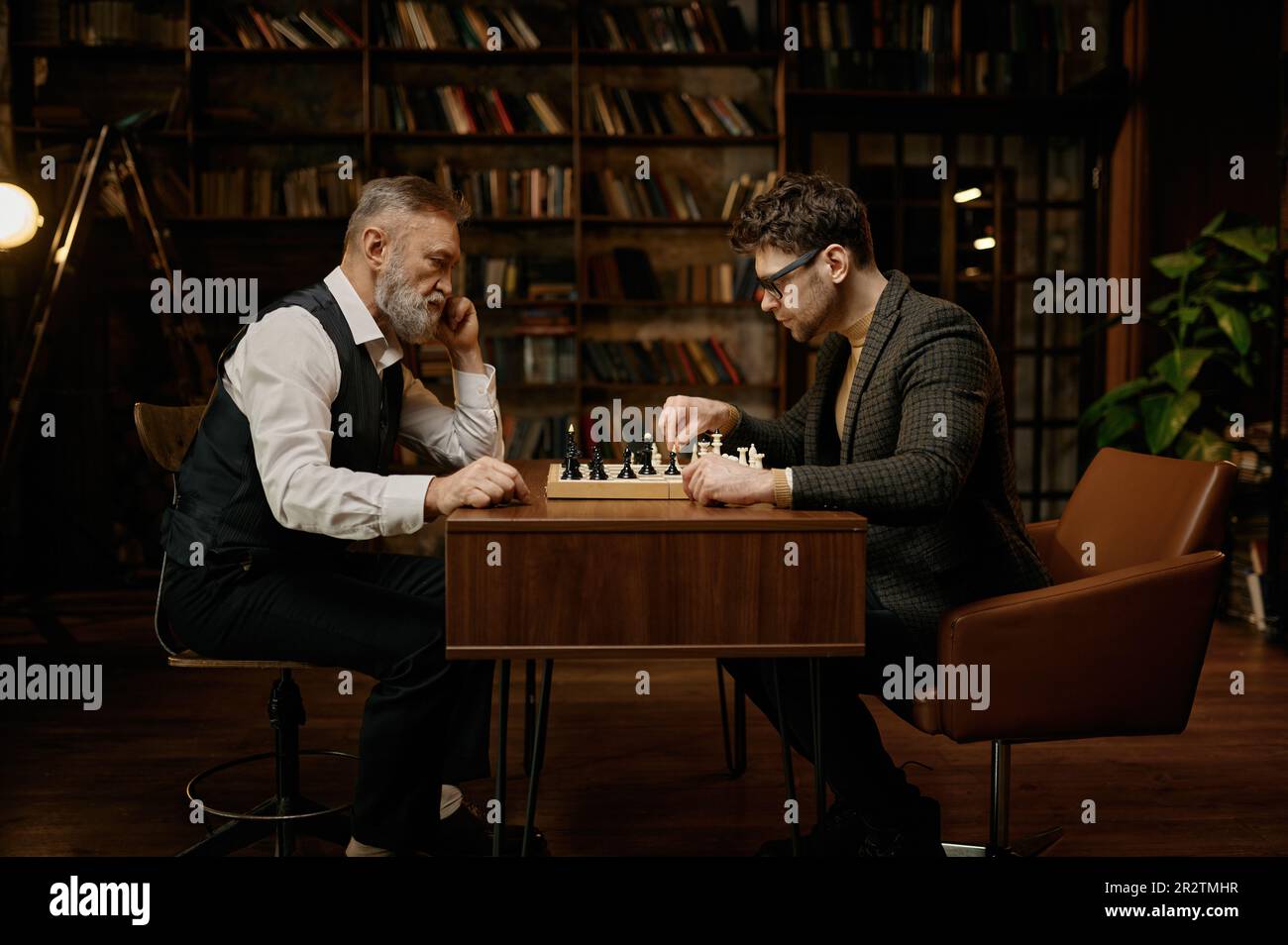 Side view on senior man and young guy chess player having friendly ...
